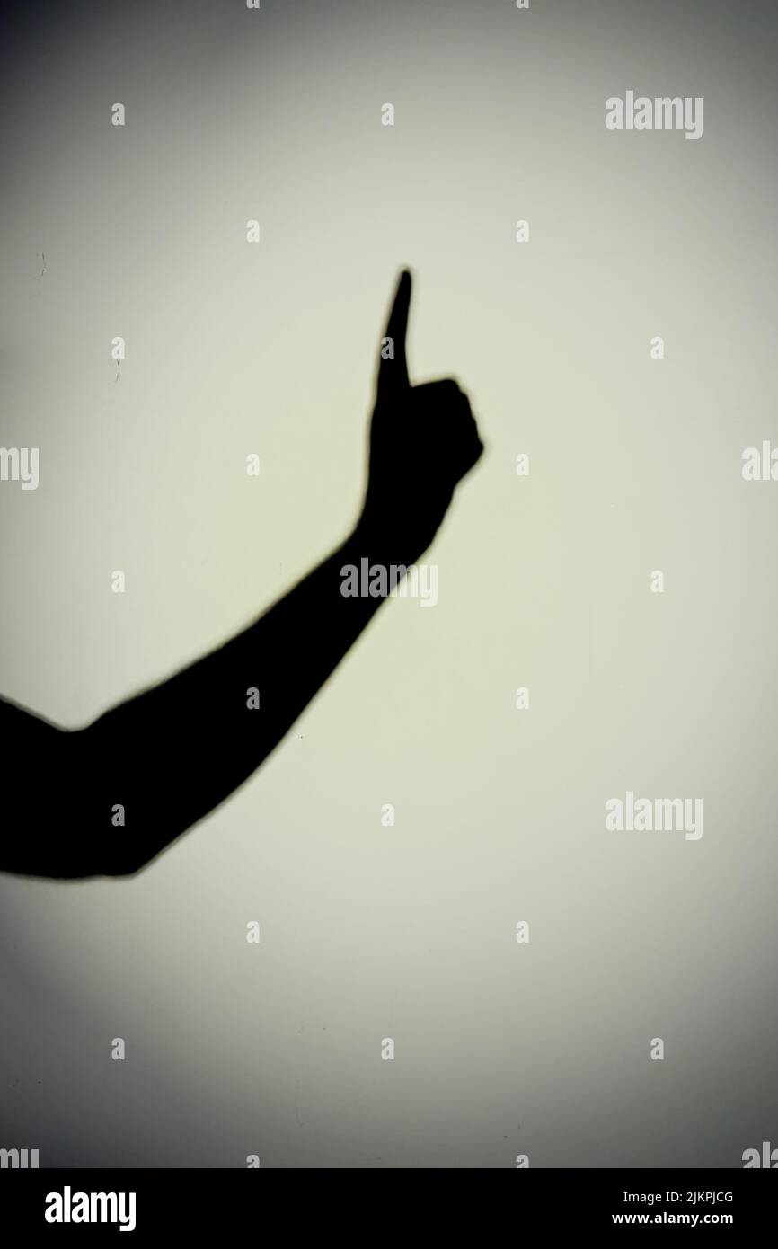 Shadow of a hand from the night light of a flashlight on a white wall ...