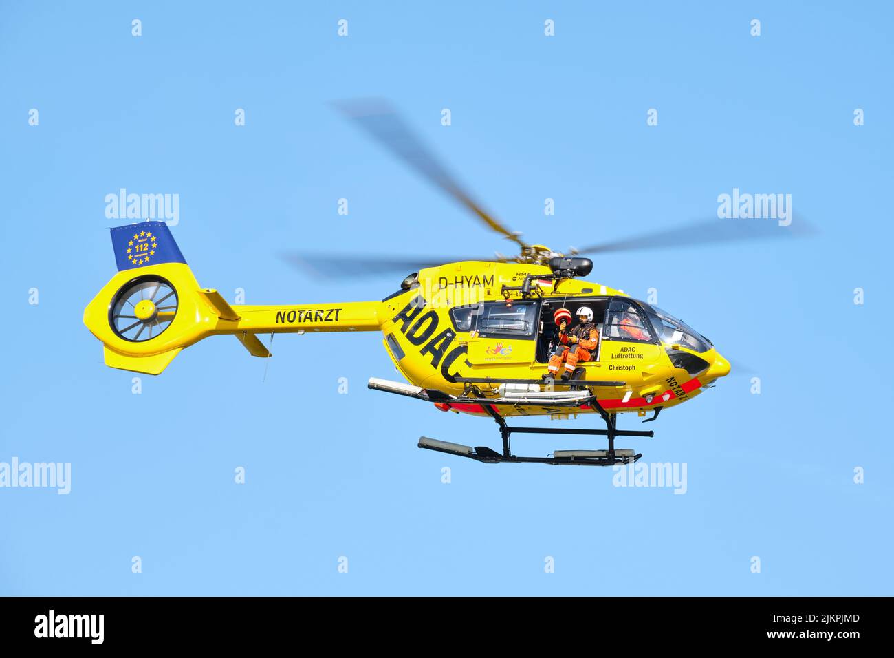 Flying rescue helicopter in front of blue sky. German ADAC air ...