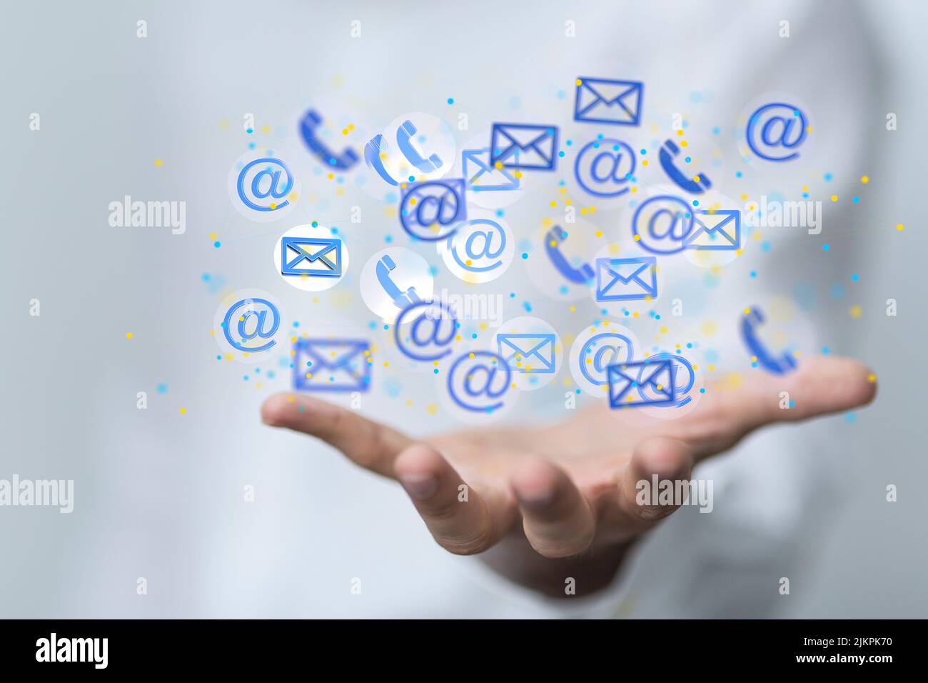 A number of communication icon illustrations above a hand on a blurred ...