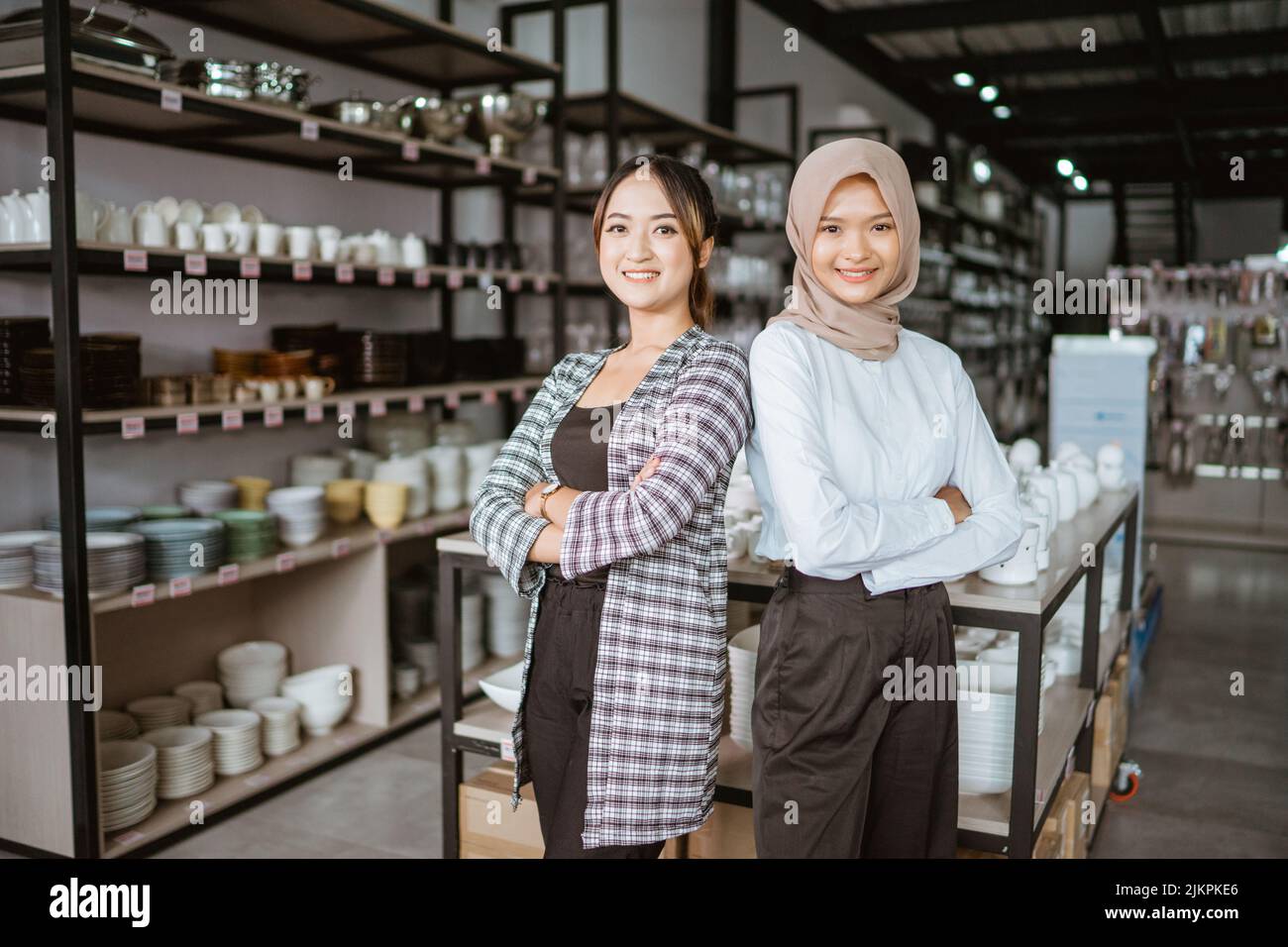 Two asian girls back to back with arms crossed Stock Photo - Alamy