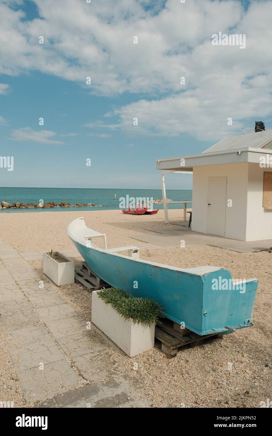 A vertical view of a blue stone bench at the beach on a blue cloudy sky ...