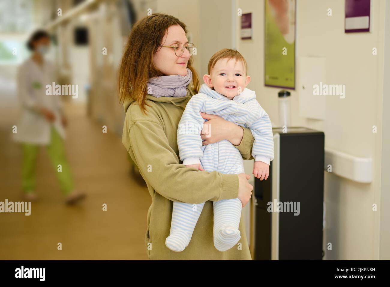Mother woman with toddler baby boy in her arms visit in the hall clinic ...