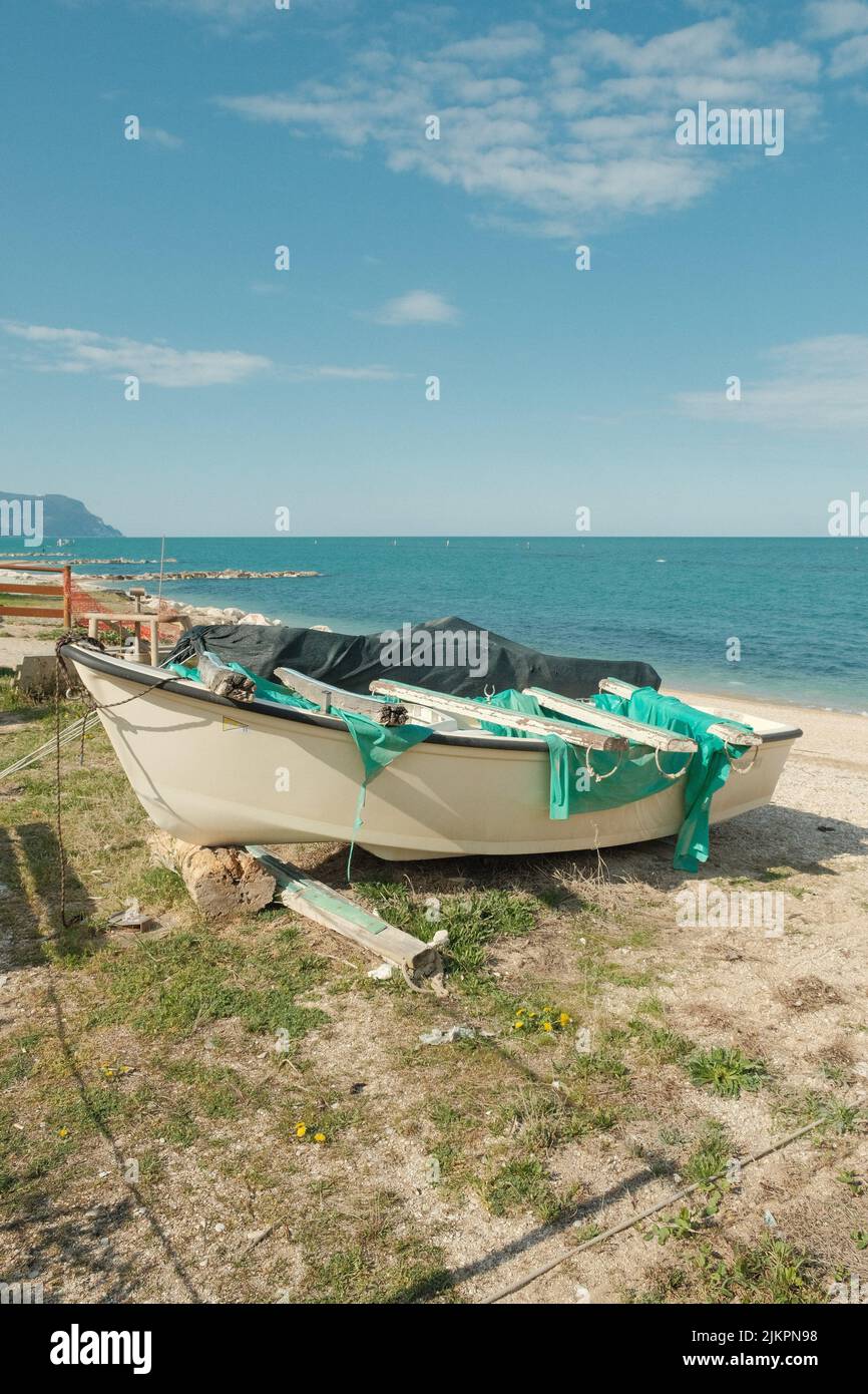 A vertical shot of a small white boat on the beach with crystal clear ...