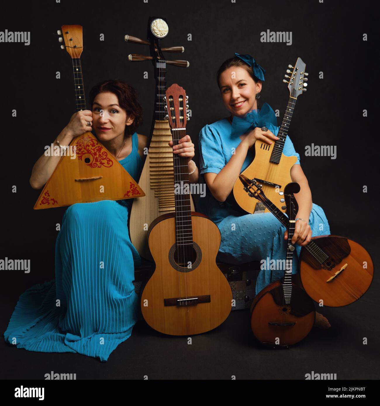Women musicians in blue dresses with musical instruments on a black ...
