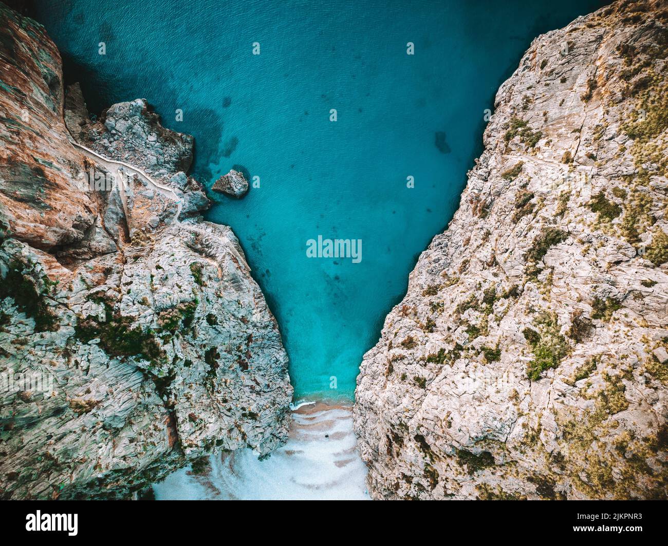 An aerial shot of a gorge with a water body and two massive cliffs from ...