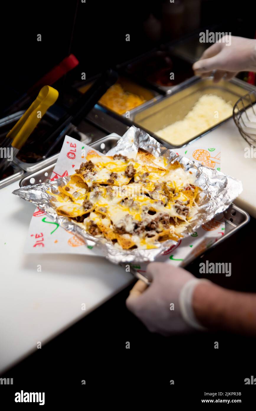 A vertical shot of a chef preparing Mexican nachos with steak in a ...