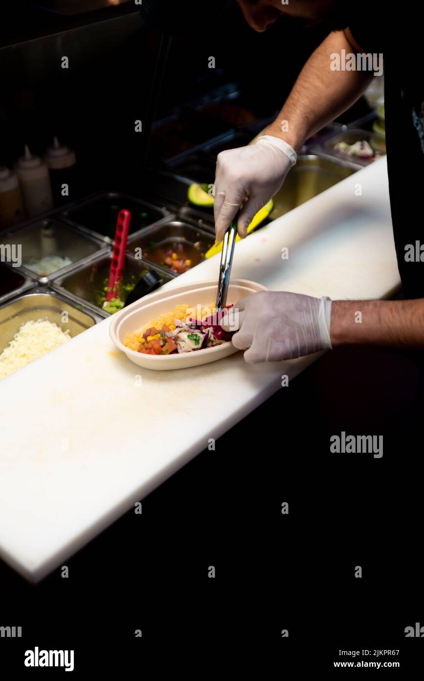 A vertical shot of a chef preparing a fish salmon bowl at a Mexican ...