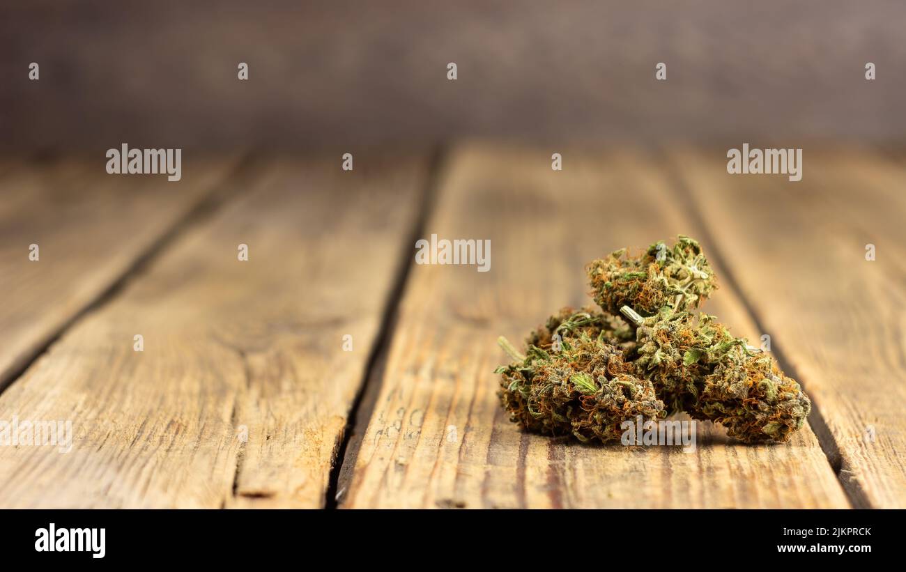 Dried buds of medical marijuana lie in a slide on a wooden background ...