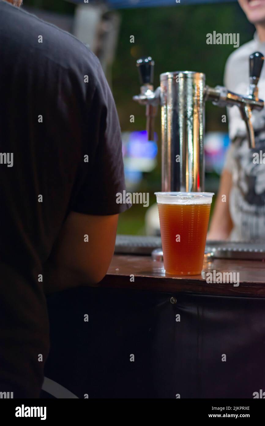 A serving of fresh beer in a plastic cup on a counter Stock Photo - Alamy