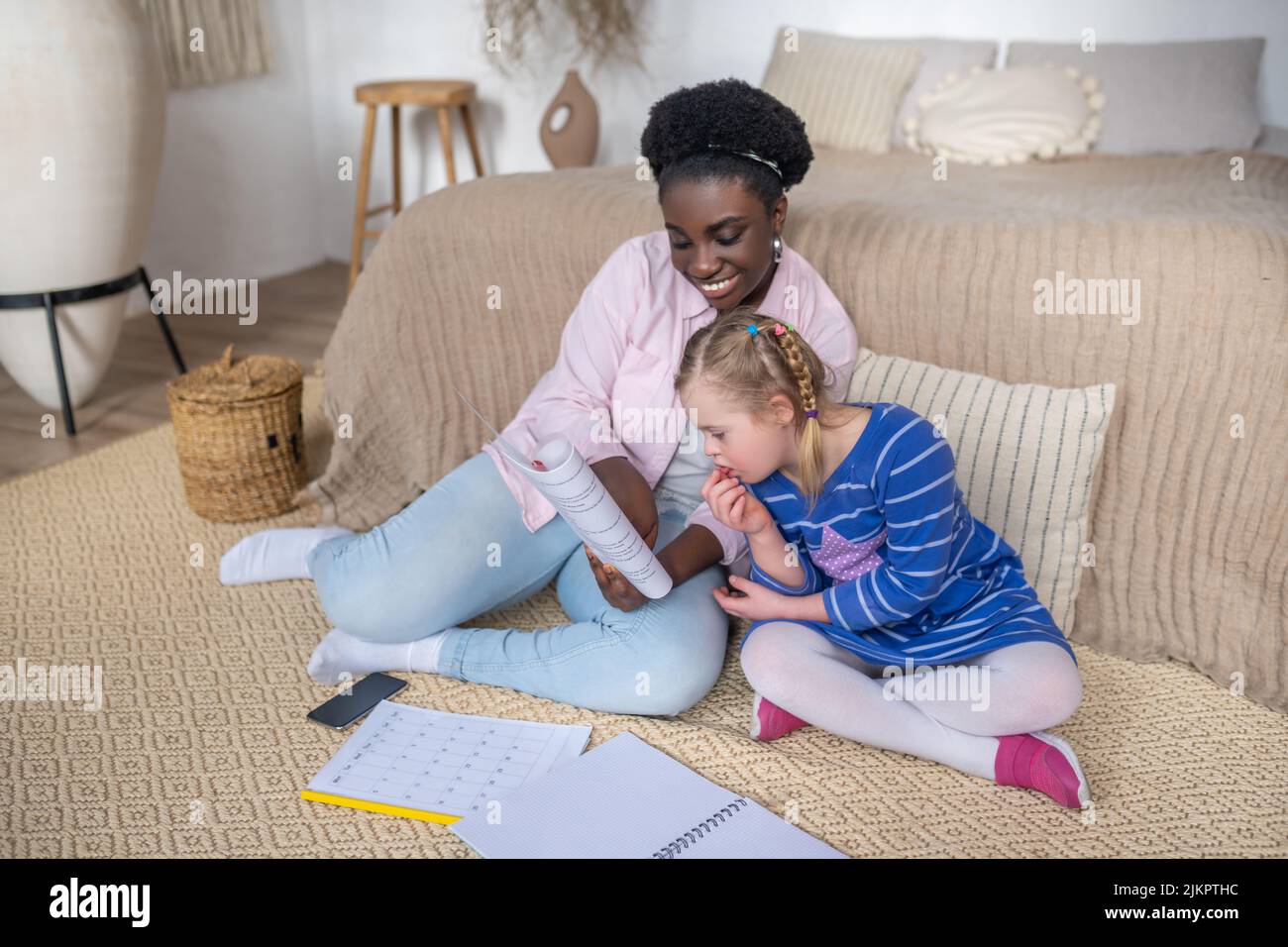 Dark-skinned woman reading something to a girl with down syndrome Stock ...