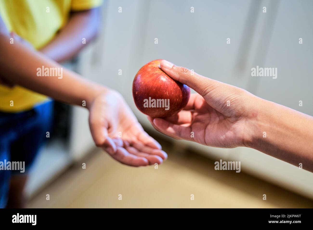 Say please. an unrecognizable woman giving a child an apple Stock Photo ...