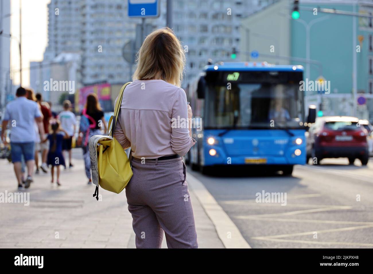 Girl standing at the stop and waiting to board the bus, public ...