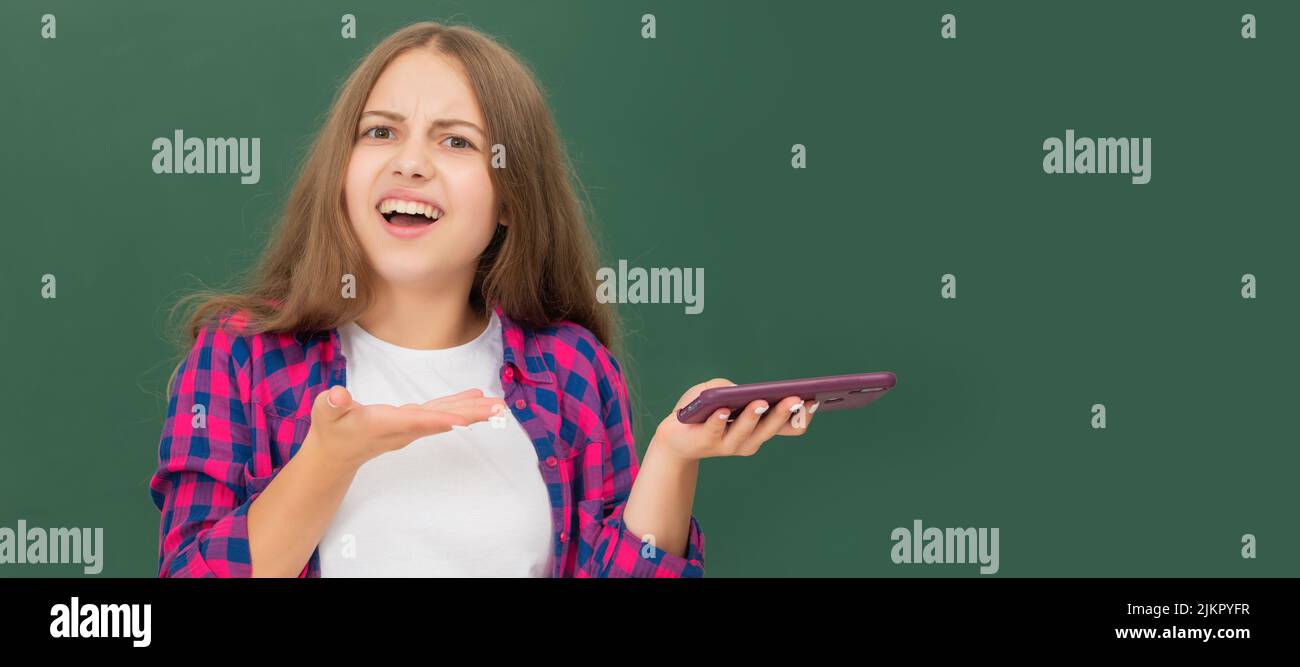 confused child at school chatting on phone on blackboard background ...