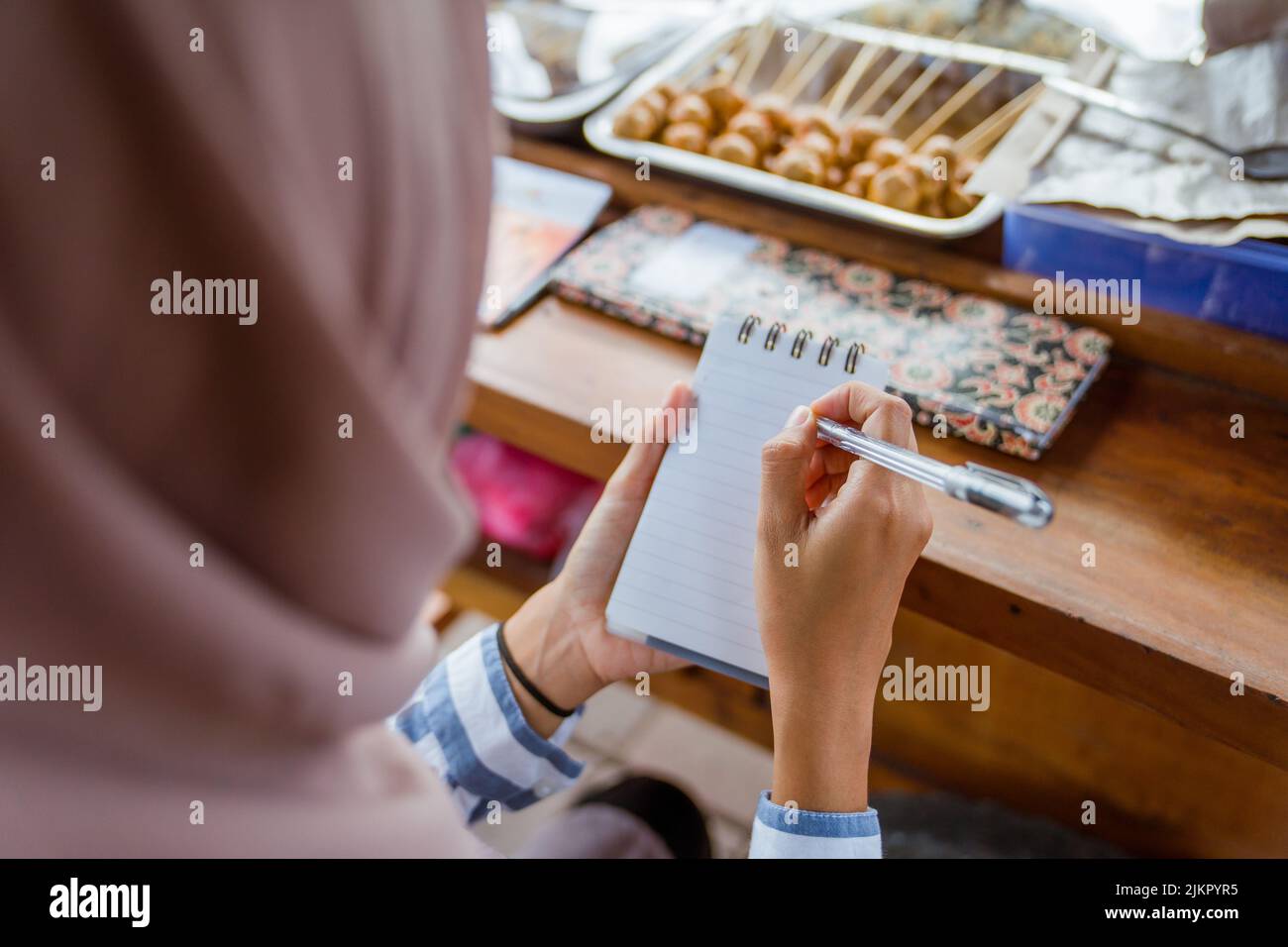 muslim woman write customer's order on a small note Stock Photo - Alamy
