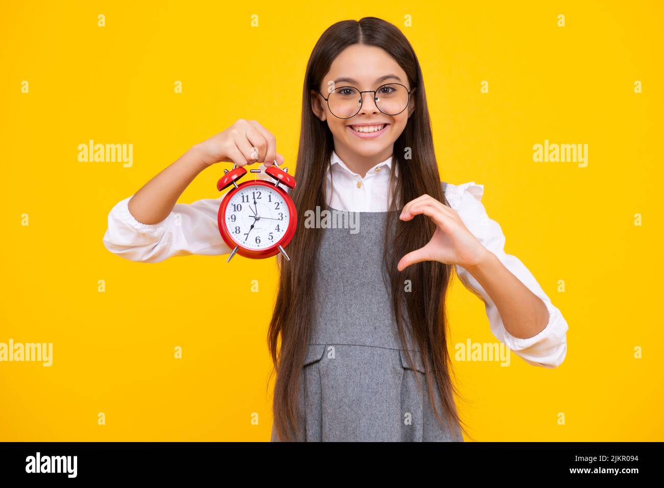 Child teenager girl with alrm clock isolated on yellow background. Time ...