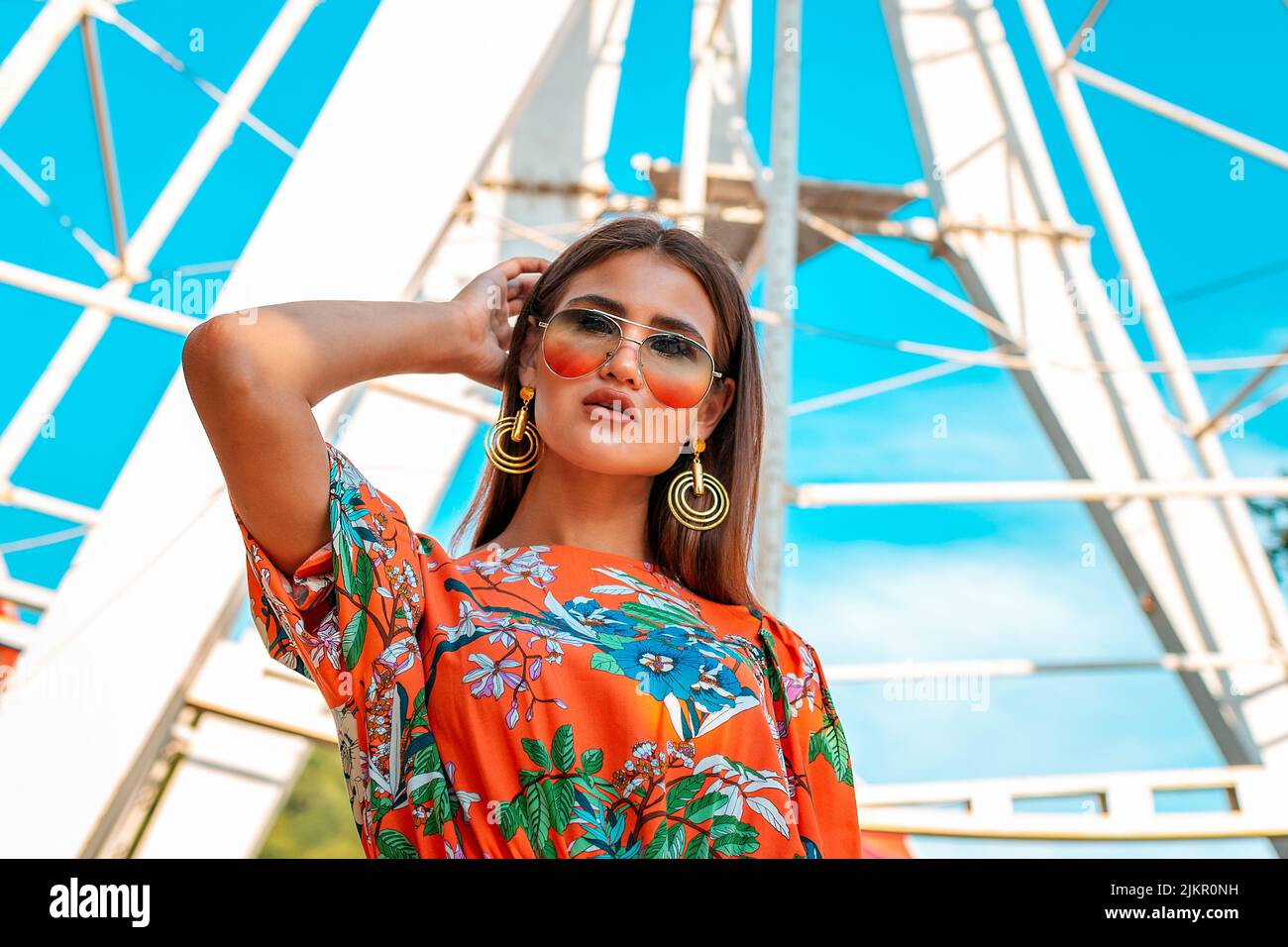 Portrait of a beautiful woman in a dress and glasses, posing against ...