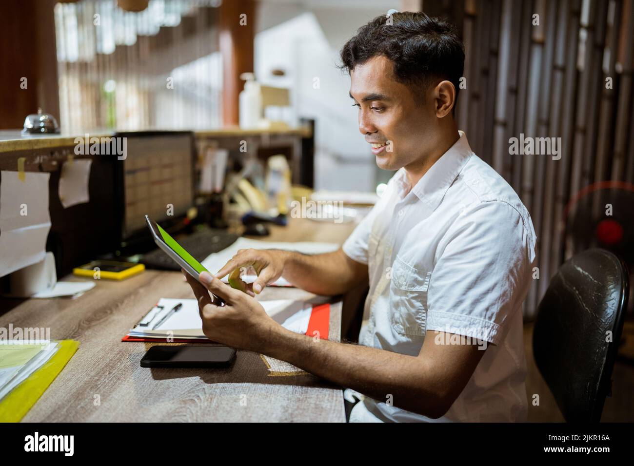 side view of receptionist using pad at hotel reception desk Stock Photo ...