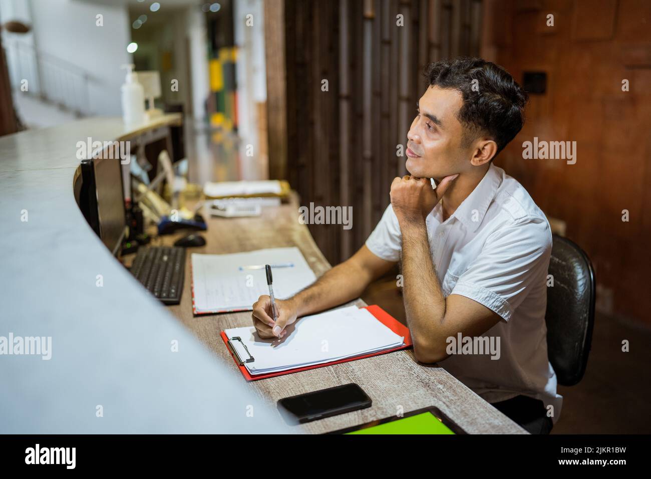 receptionist write while sitting at hotel reception desk Stock Photo ...