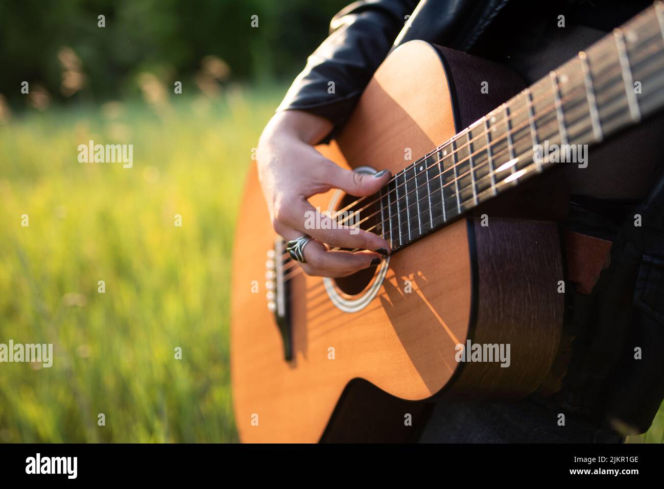 Woman musician playing guitar in nature at sunset Stock Photo - Alamy