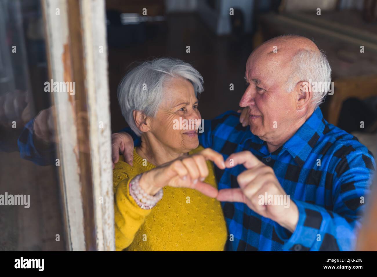 Sweet caucasian senior couple standing together, looking at each other ...