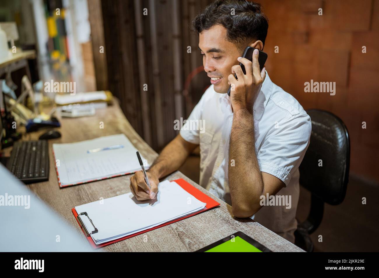 receptionist takes a phone call and takes notes on paper Stock Photo ...