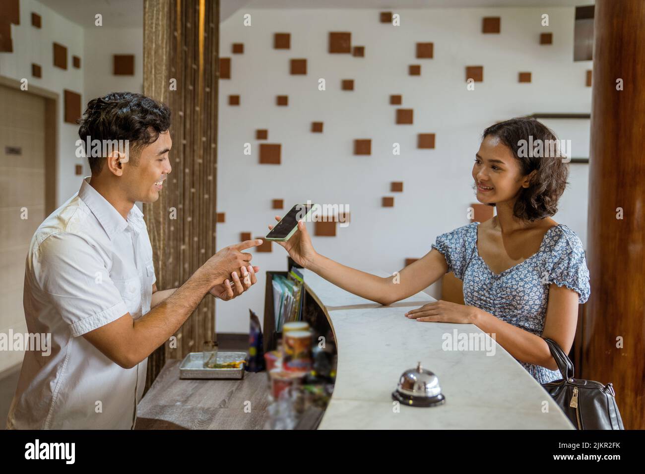 Female guest showing smartphone at receptionist for proof of booking ...