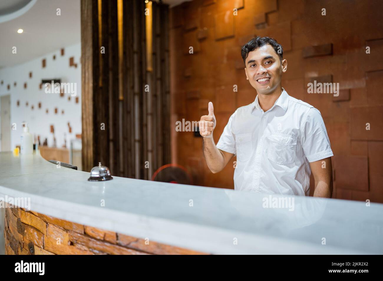 receptionist smiling with thumbs up while standing on reception desk ...