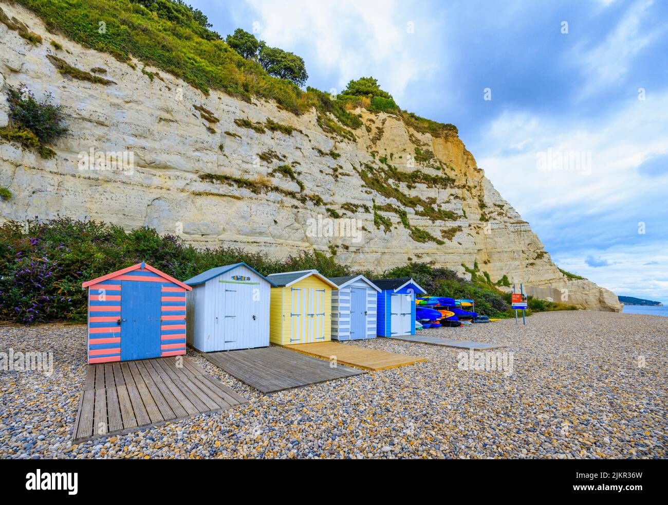 A row of beach huts at the foot of chalk cliffs at Beer, a small ...