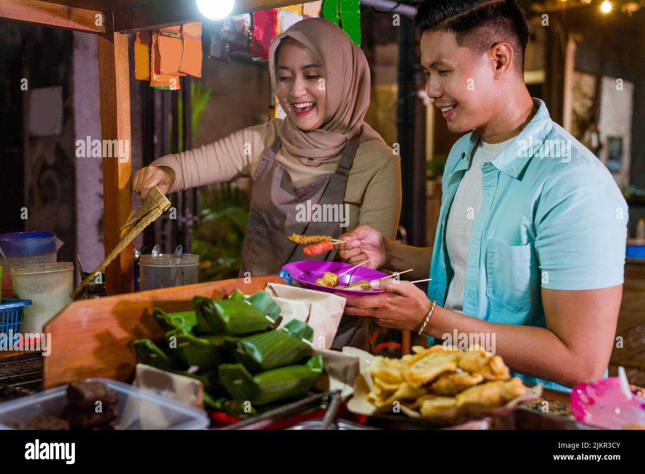 asian muslim couple enjoy grill their food at traditional stall Stock ...