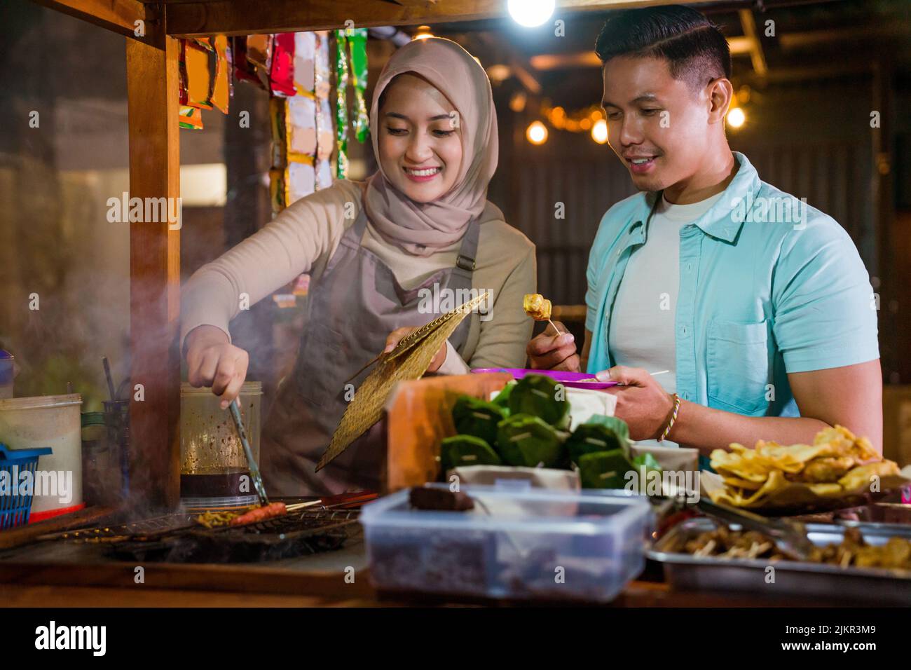 asian muslim couple enjoy grill their food at traditional stall Stock ...