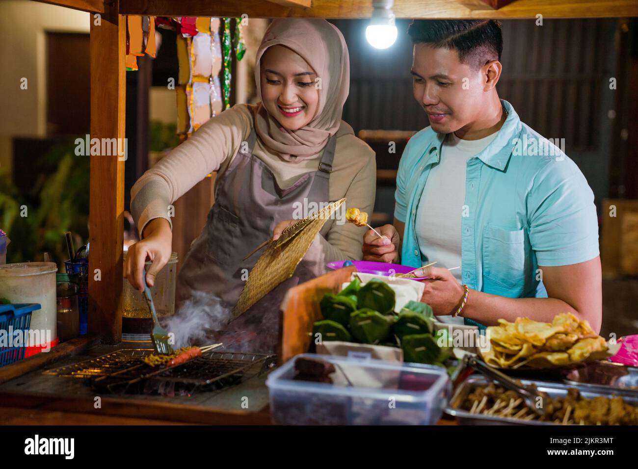 asian muslim couple enjoy grill their food at traditional stall Stock ...