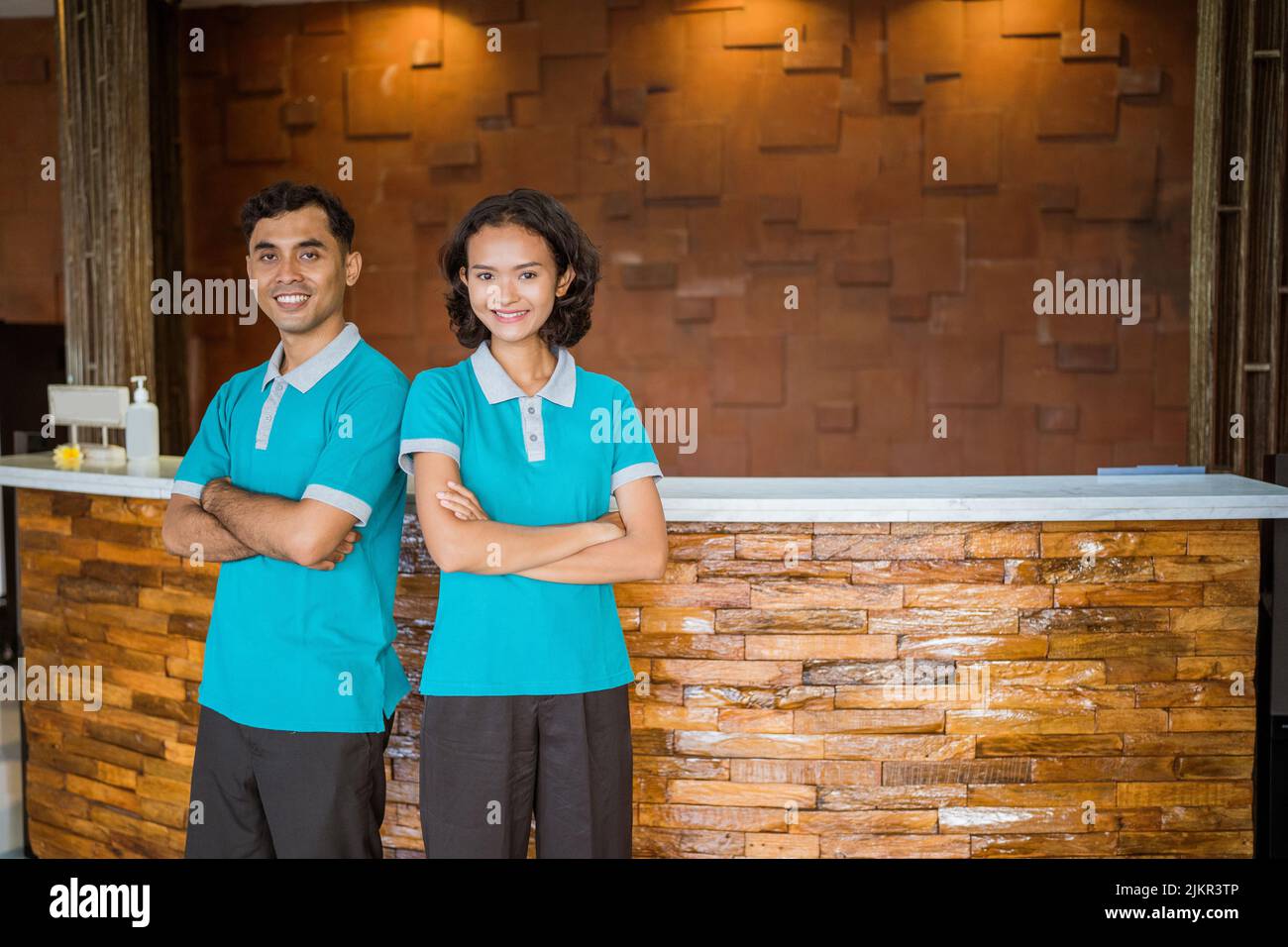 two receptionists standing with hands crossed against reception desk ...