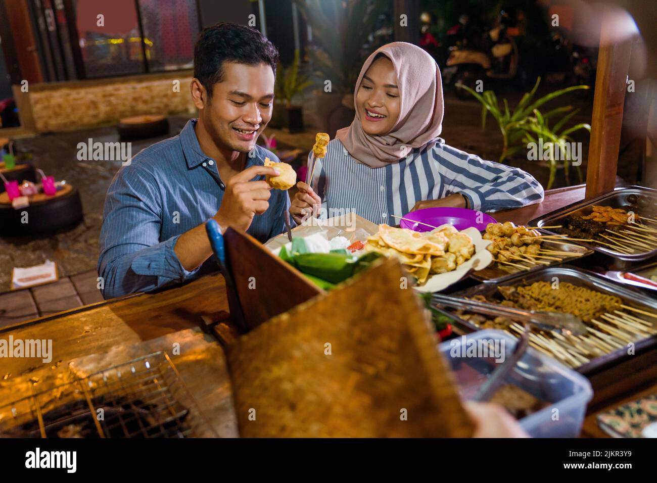 muslim couple enjoying having dinner out at traditional food market ...