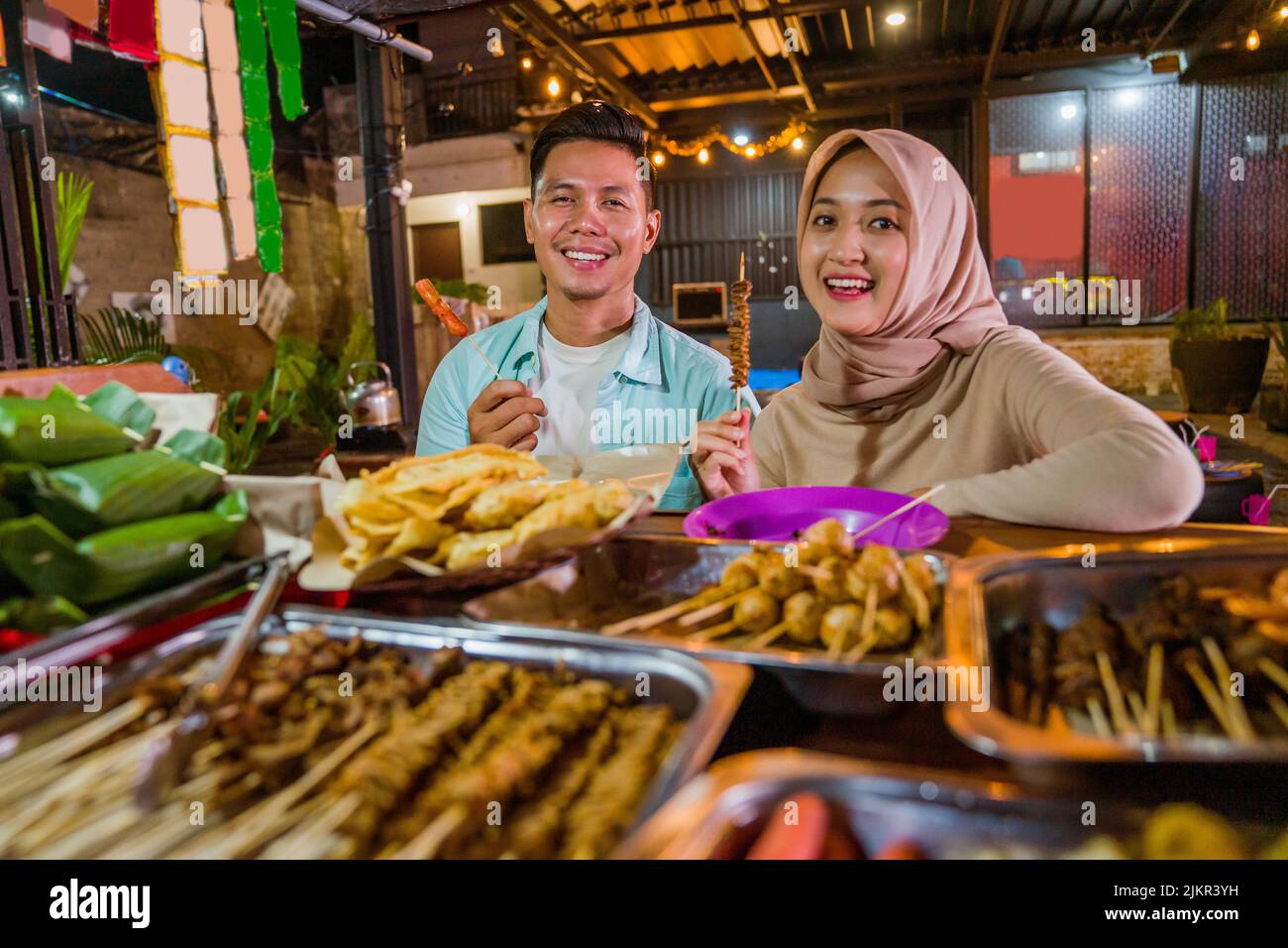 couple smiling at camera having dinner out at traditional food stall ...