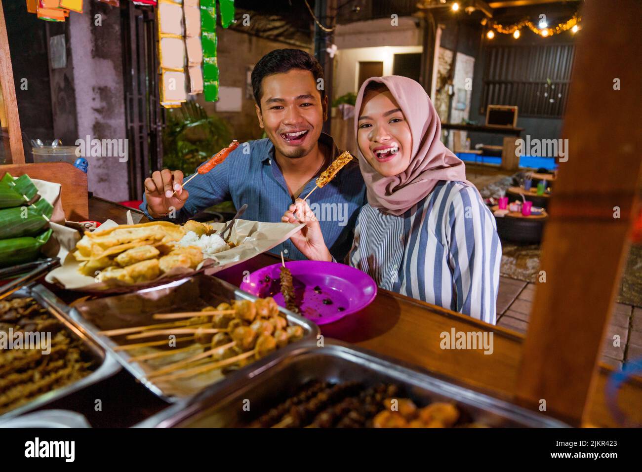 couple smiling at camera having dinner out at traditional food stall ...