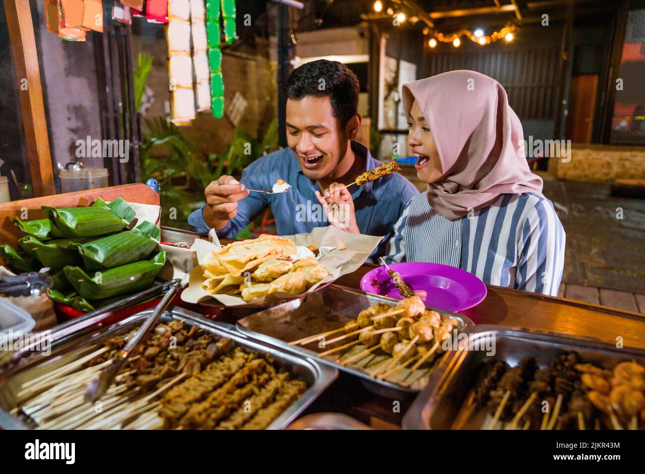 muslim couple enjoying having dinner out at traditional food market ...