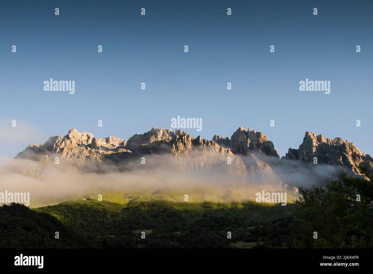 The morning clouds hover over the mountain rocky peaks in a soft light ...