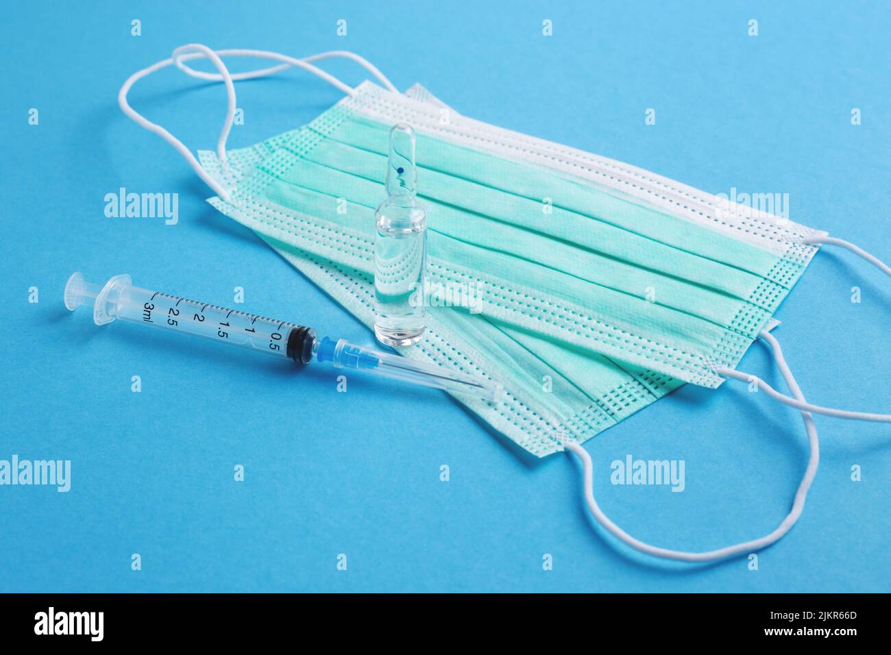 Medical blue background with injection needle, glass ampoule and ...