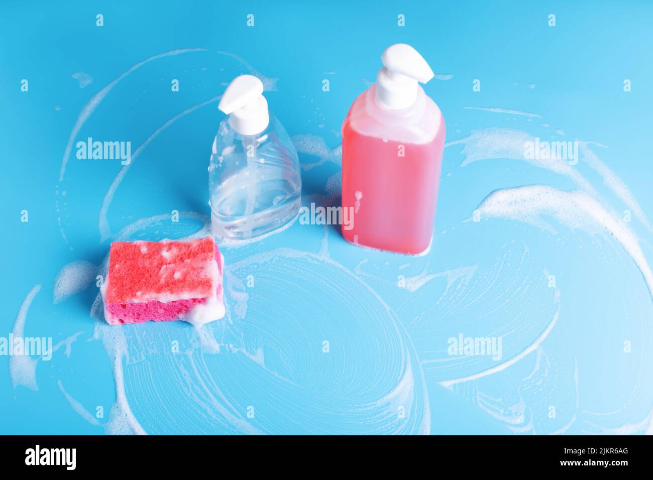 Spring cleaning. Soapy red sponge with two bottles of cleaning soap on ...