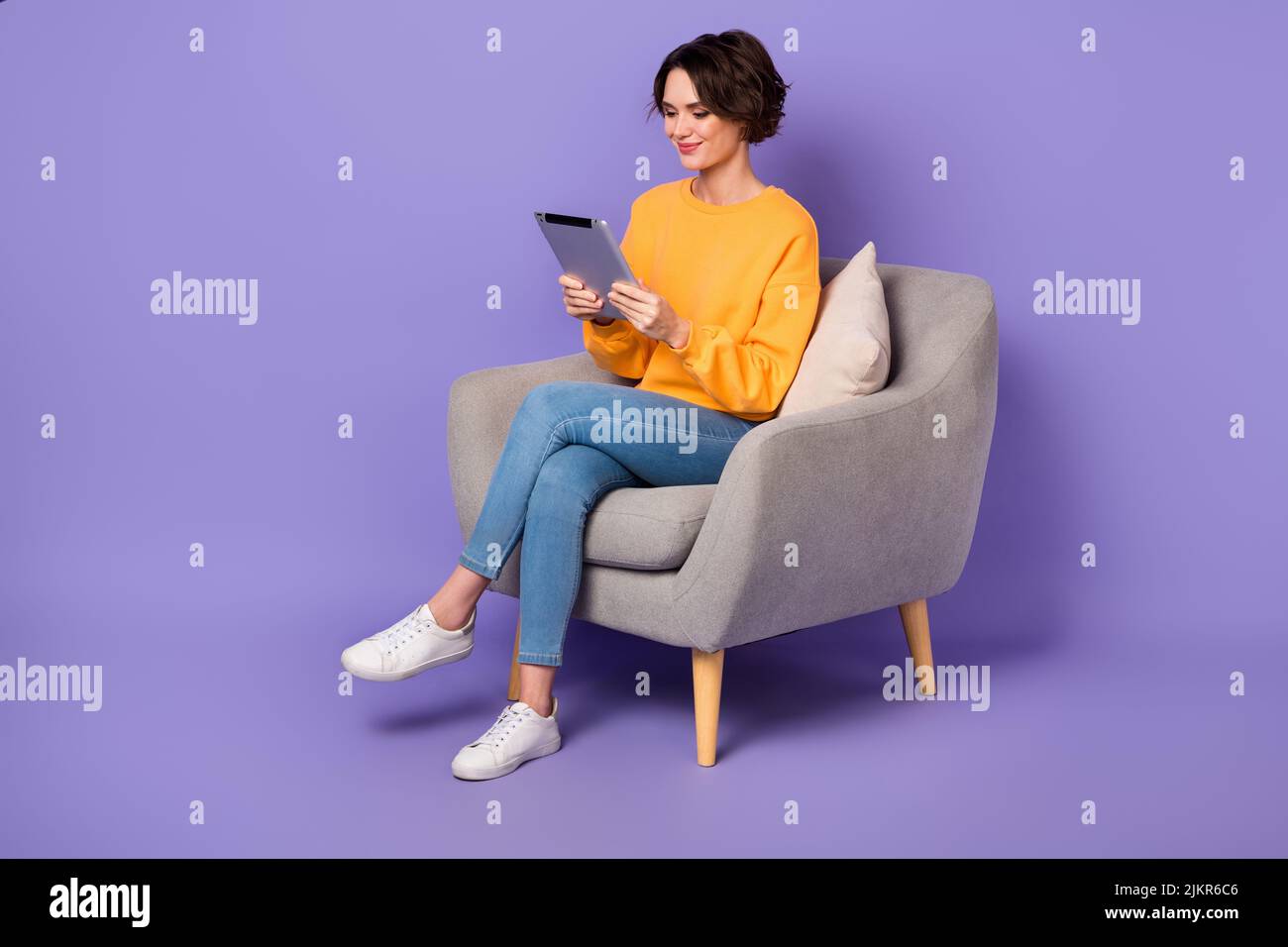 Full body photo of charming positive person sit chair hold use tablet ...