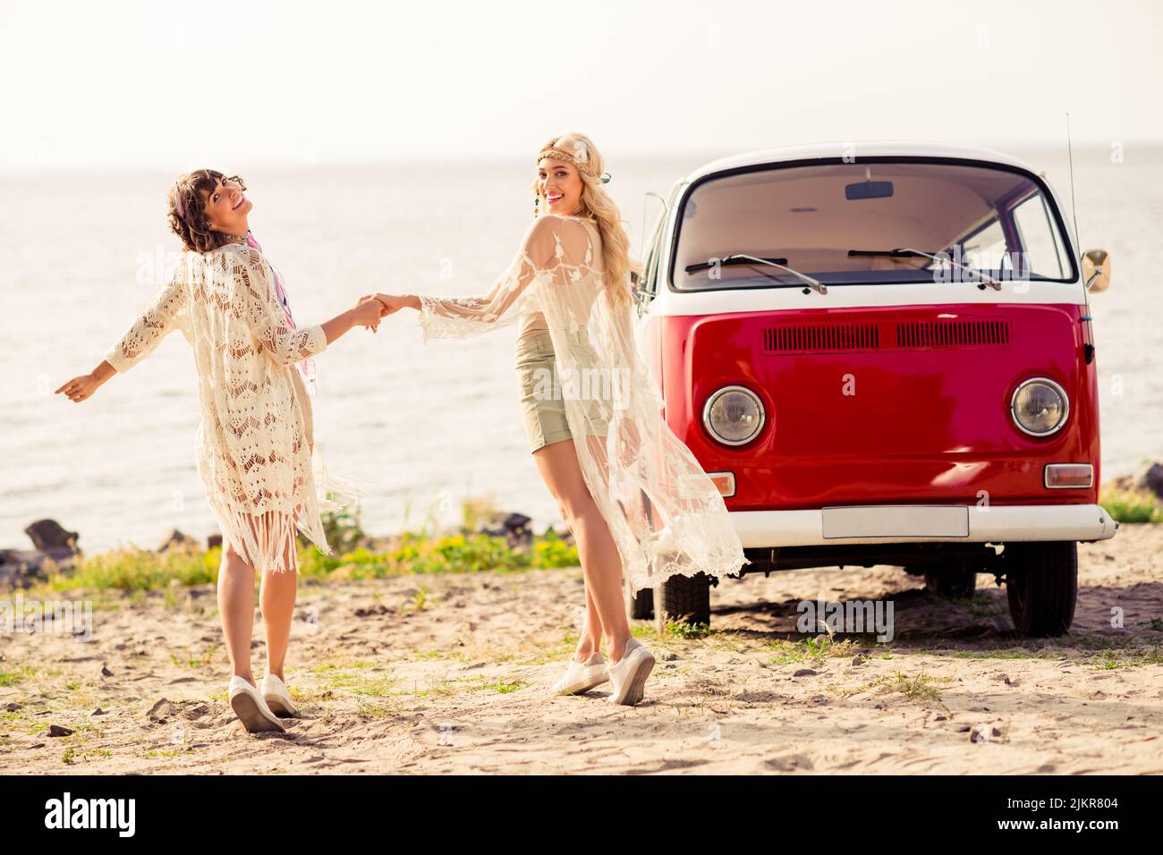 Full body rear behind portrait of two positive pretty girls hold arm ...
