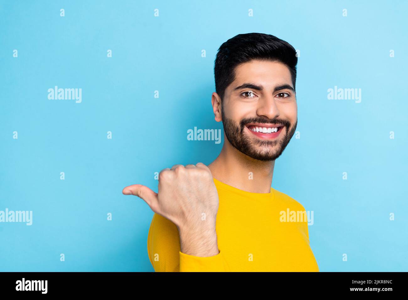 Photo of cute handsome man wear yellow sweater pointing thumb back ...