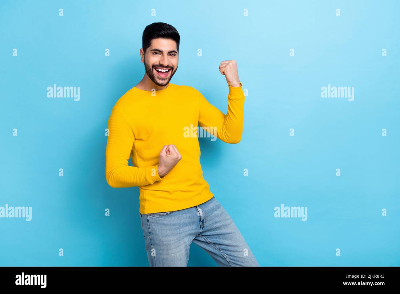 Photo of funky lucky man wear yellow sweater rising fists empty space ...