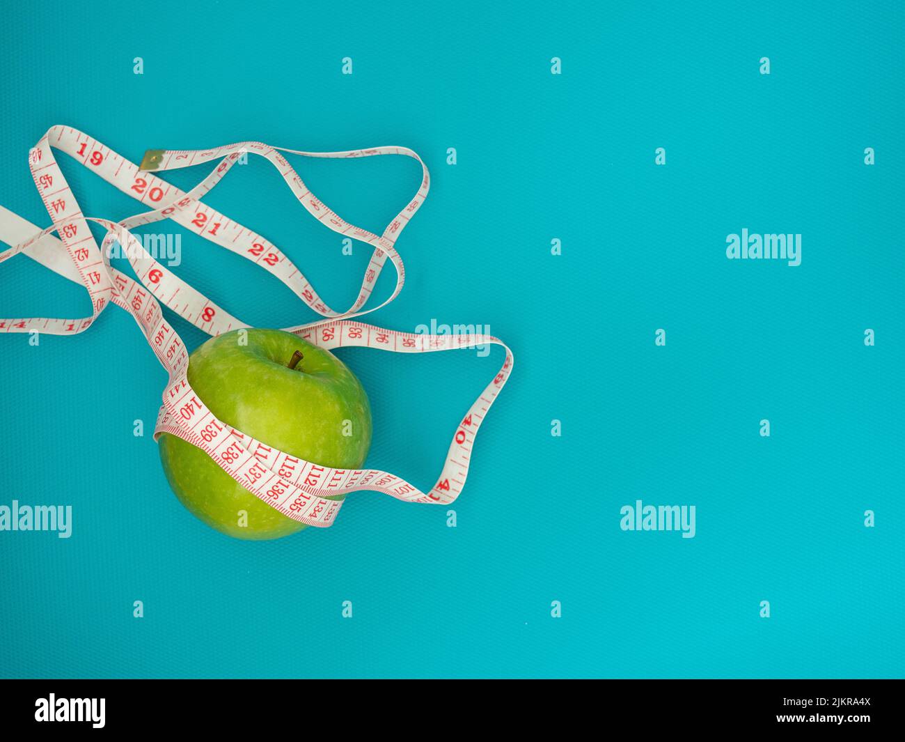 Green apple with measuring tape on blue background. The concept of ...