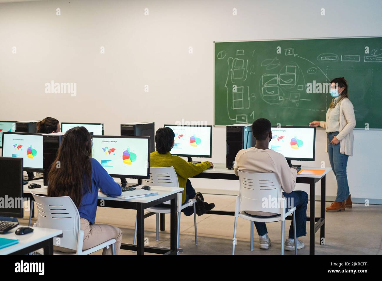 Multiracial students using computers during business class wearing ...