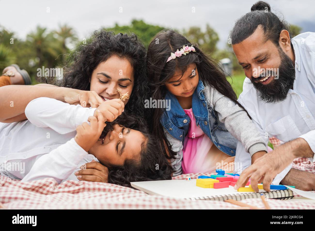 Happy indian family having fun playing with children outdoor at city ...