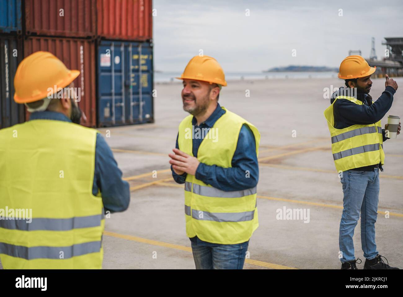 Workers controlling shipping containers at industrial port outdoor ...