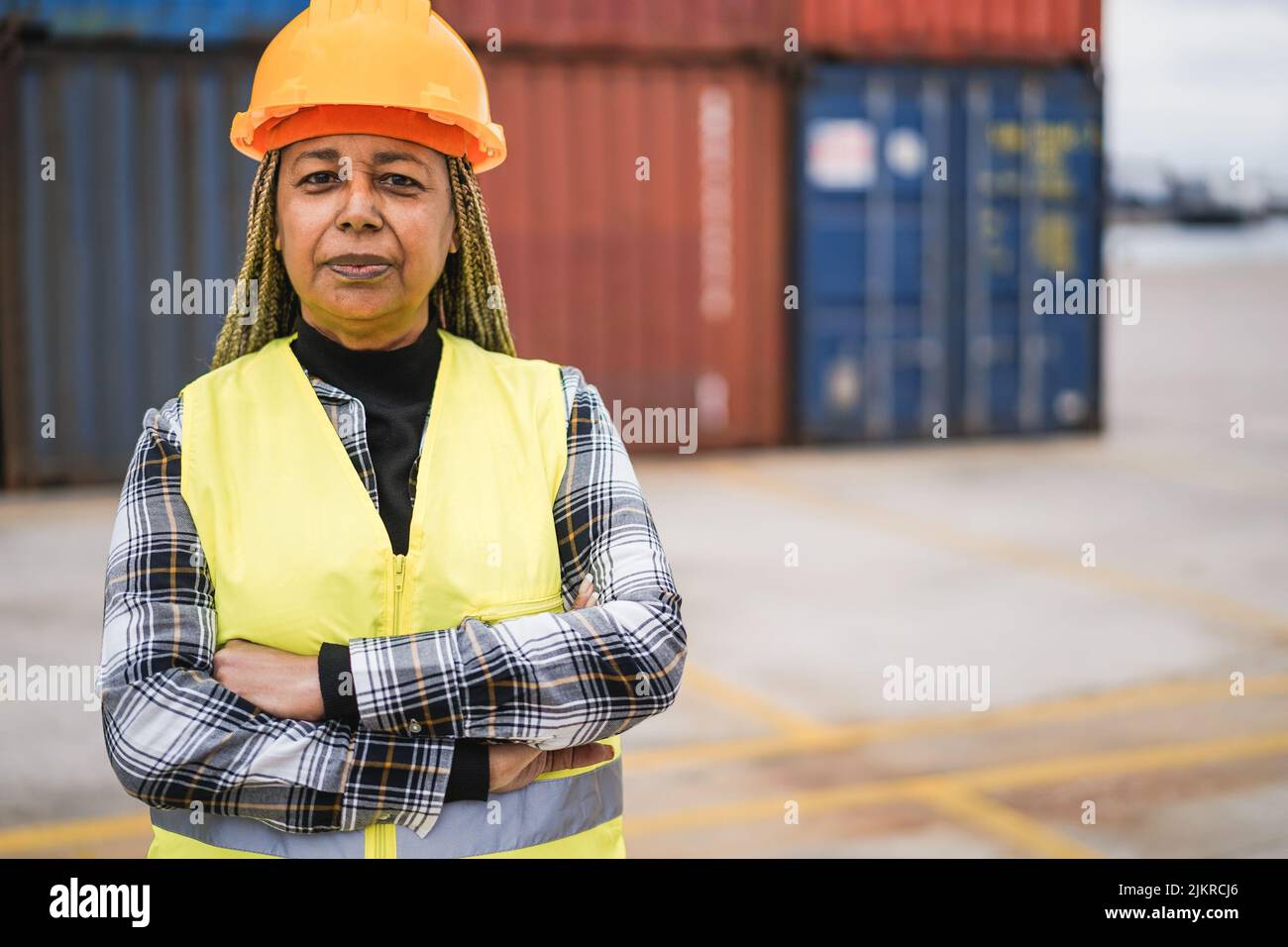 Worker African senior woman smiling on camera with industrial port on ...