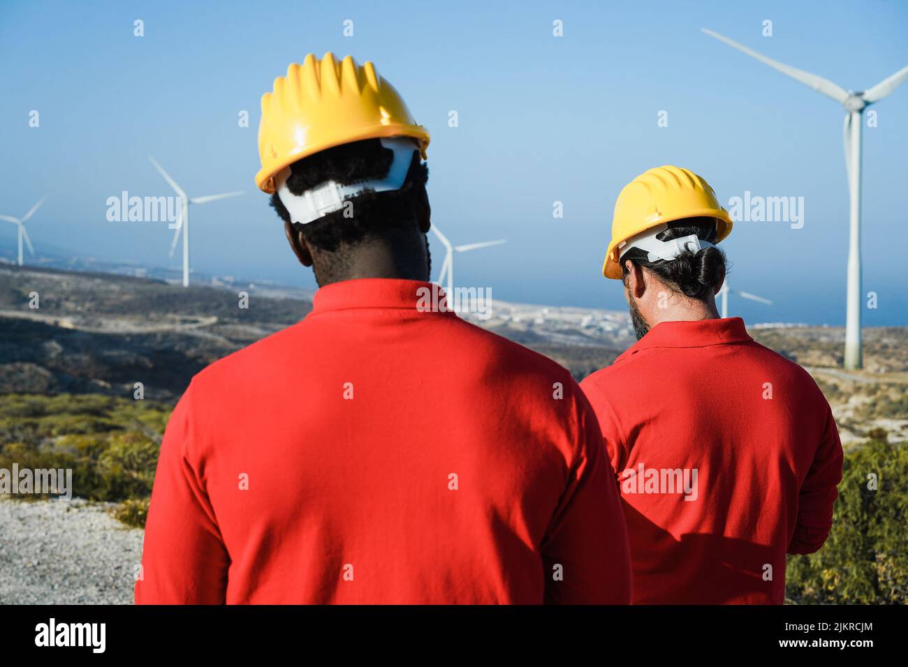 Multiracial engineers working on a windmill farm - Focus on right man ...