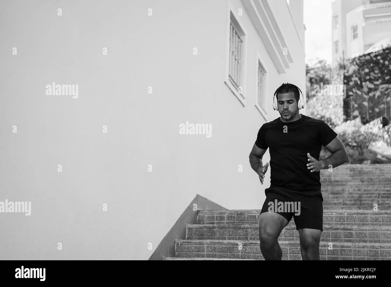 Fit hispanic man running outdoor - Focus on face - Black and white ...